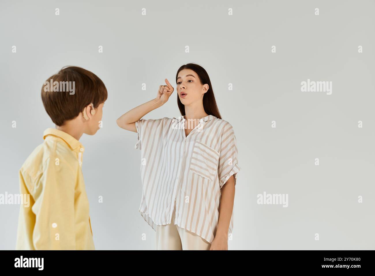 A mother guides her hearing impaired child in learning expression ...