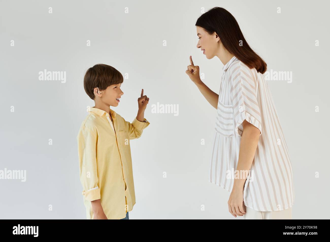 A mother engages playfully with her hearing impaired son using sign ...