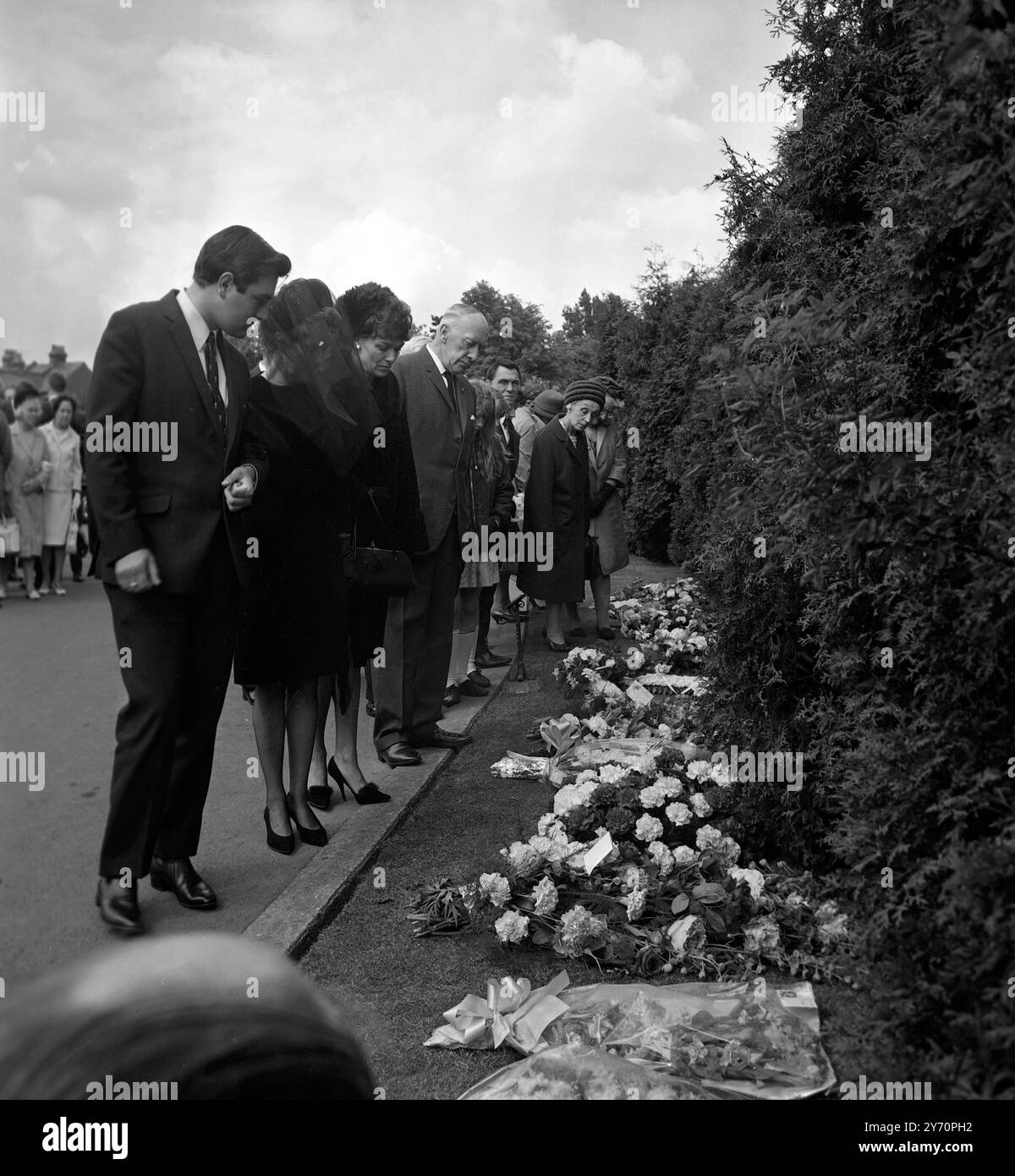 The son and wife of Mr Frederick West ( foreground ) looking at wreaths ...