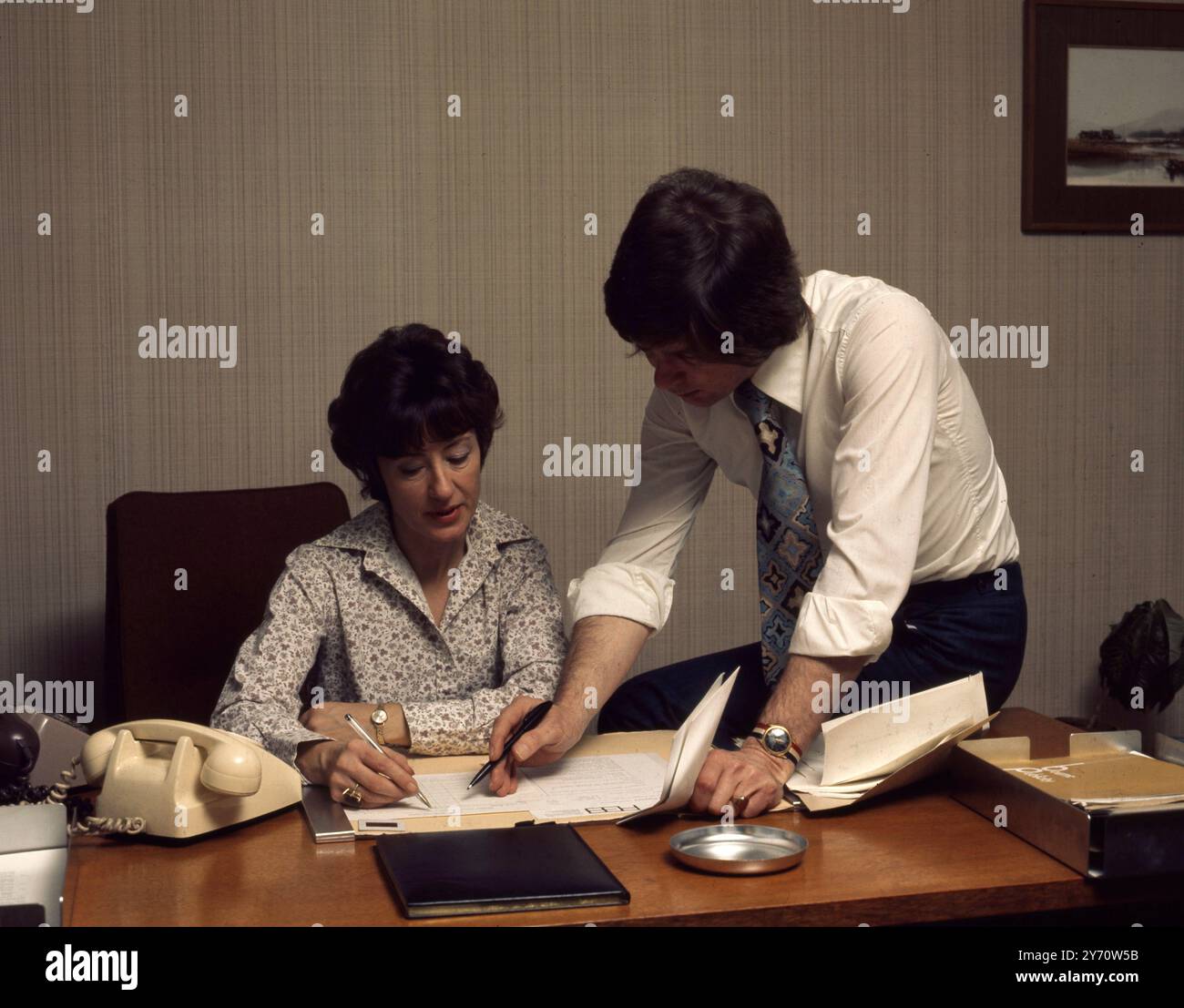 Office workers discuss an invoice 1970's Stock Photo - Alamy