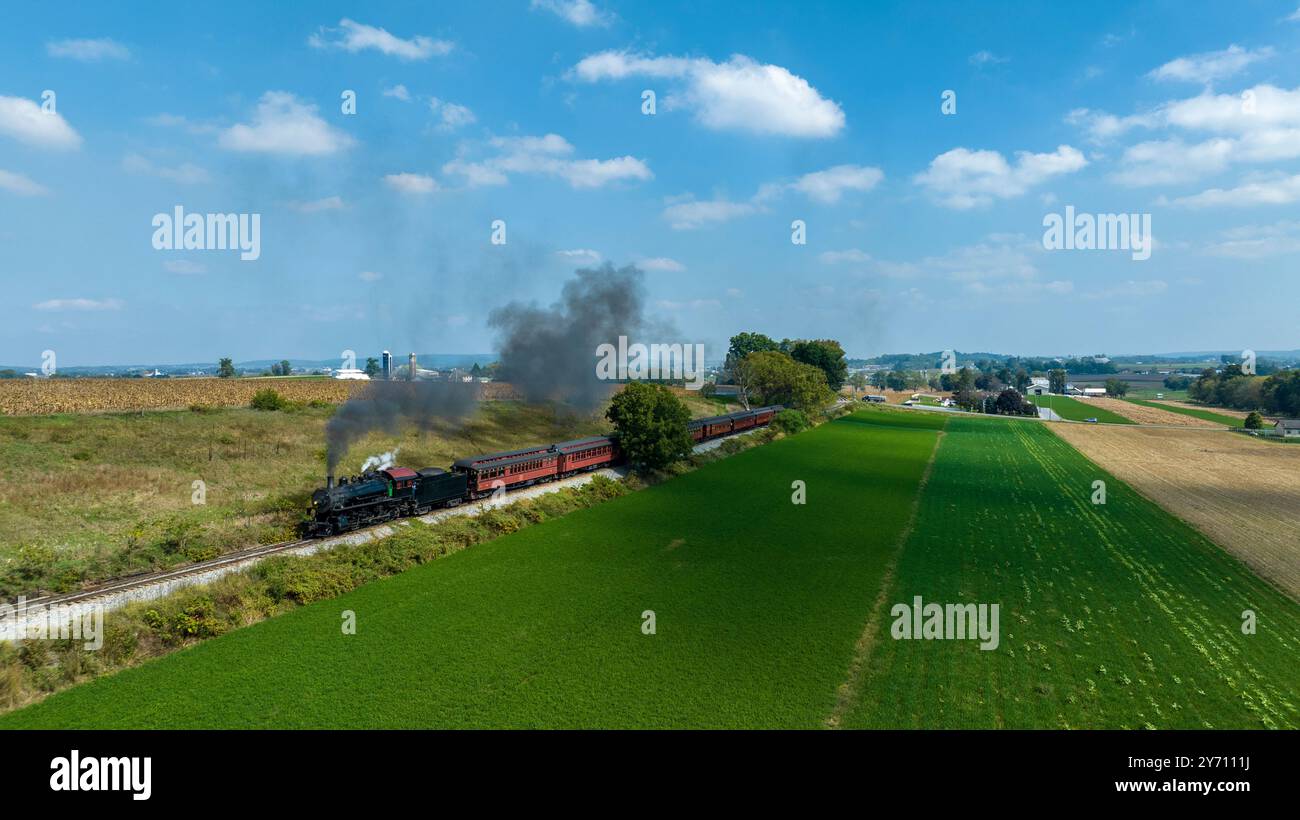 A classic steam locomotive pulls vintage carriages as it travels ...