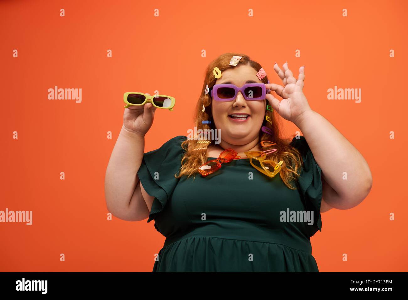 A joyful plus size woman poses with colorful sunglasses, expressing ...