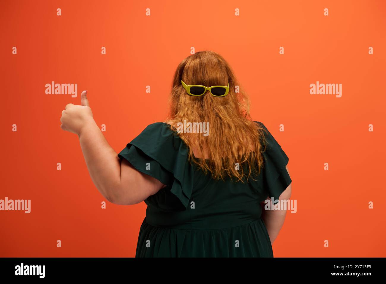 A confident plus size woman proudly shows a thumbs up while wearing ...