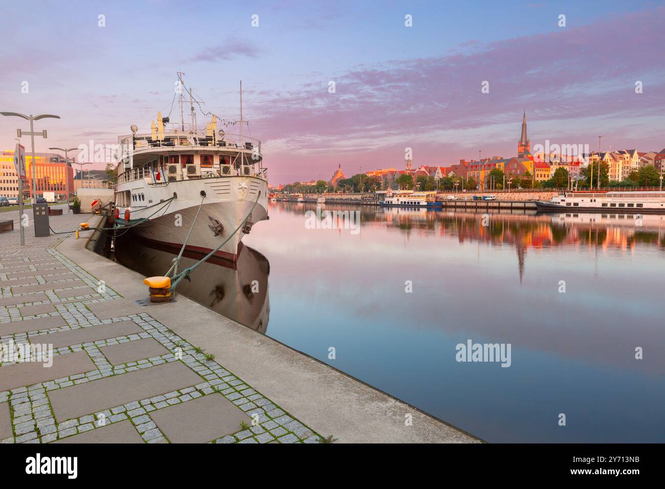 A docked ship along the Szczecin riverfront in Poland during dawn, with ...