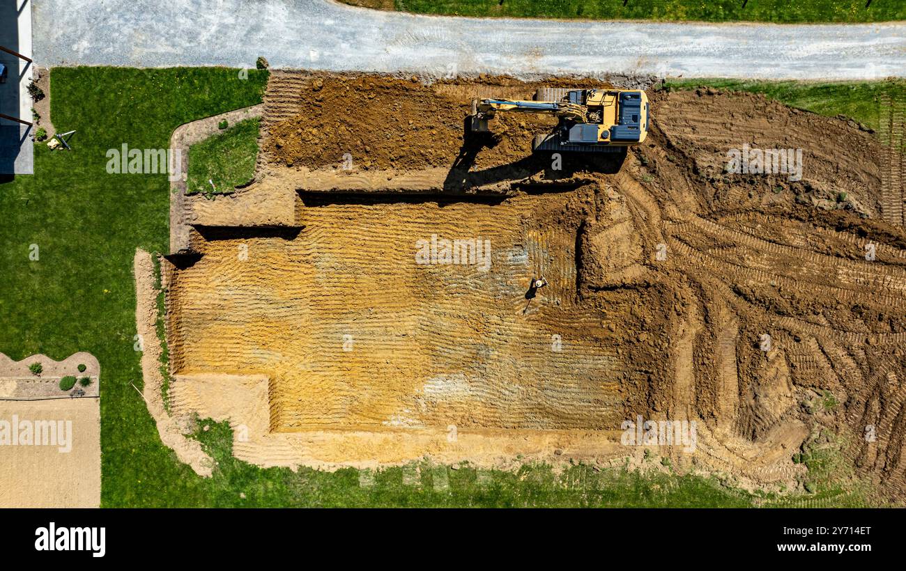 An excavator is digging into the ground to prepare a foundation for ...