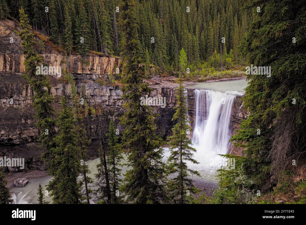 Powerful waterfall cascading down a rocky cliff surrounded by a lush ...