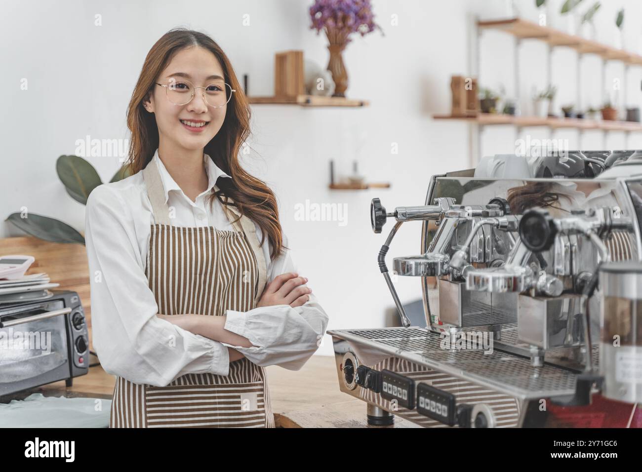 Happy young female coffee shop owner standing behind her counter next ...
