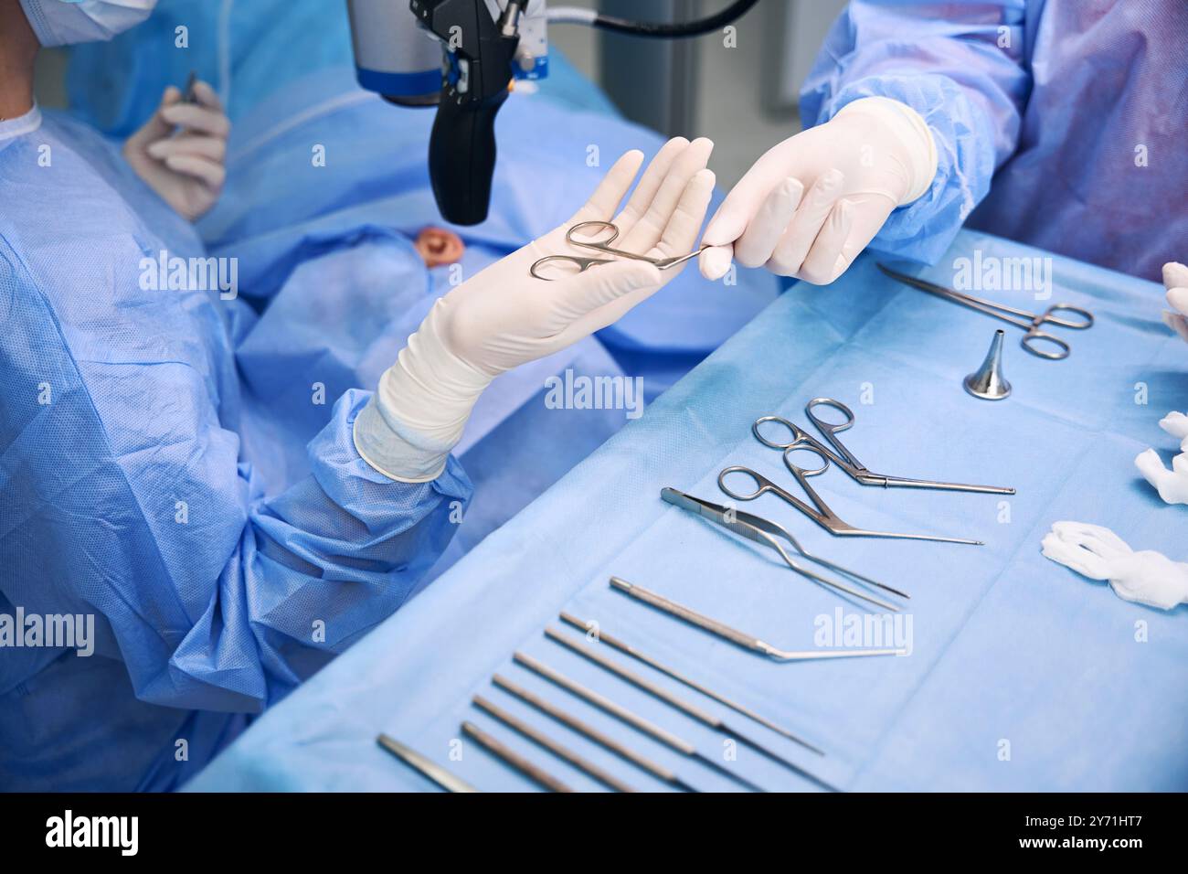 Assistant hands a surgical instrument to a surgeon Stock Photo - Alamy