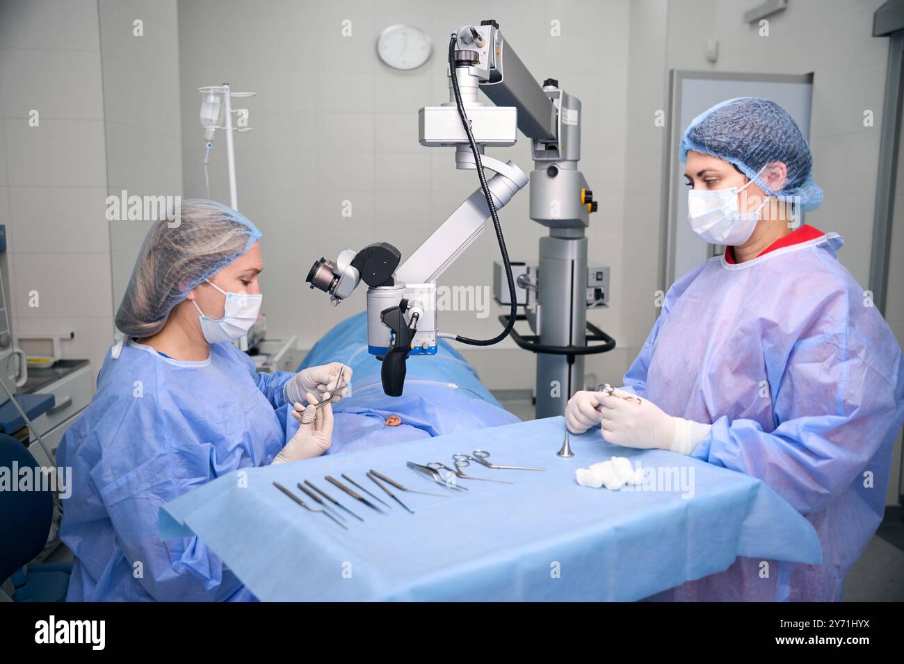 Female surgeon with assistant performing surgery in operating room ...