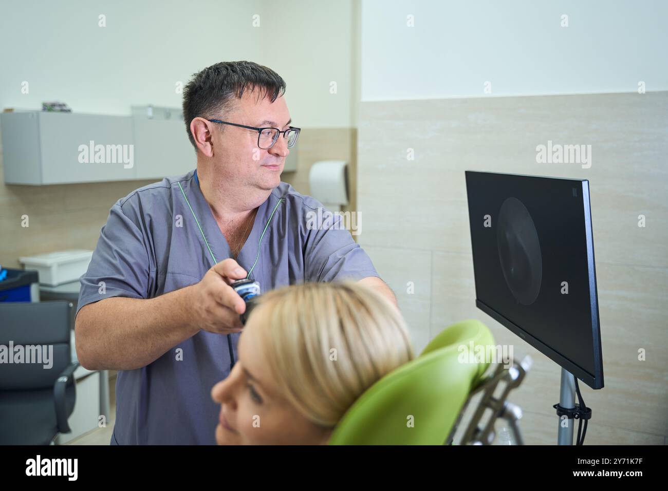 Doctor checking patients ear using medical device Stock Photo - Alamy