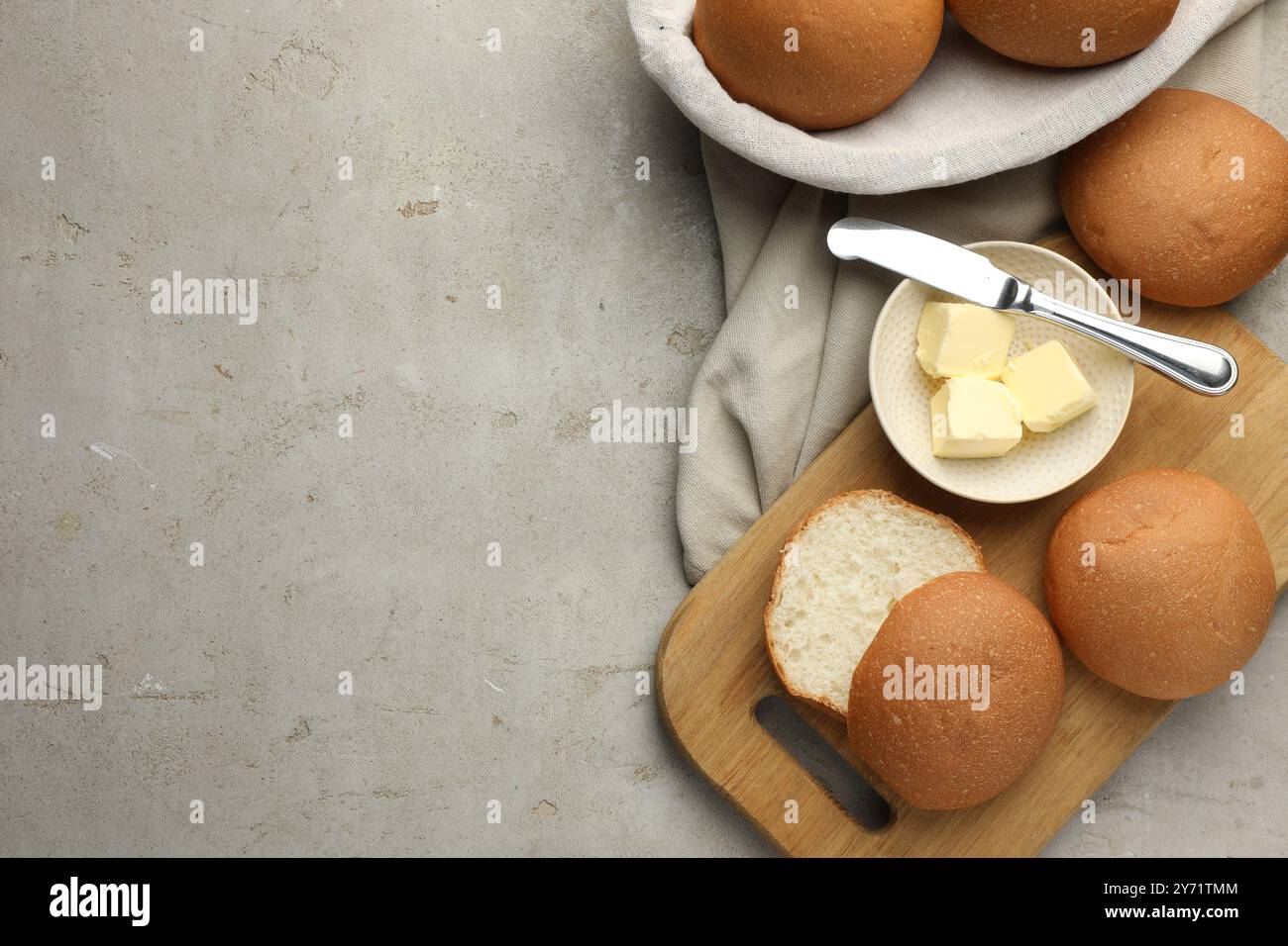Fresh tasty buns and butter on grey table, top view. Space for text ...