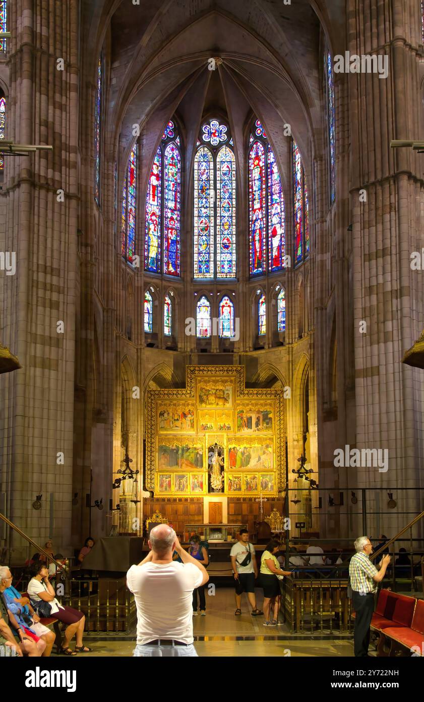 Tourist taking a mobile phone image of the high altar and stained glass ...