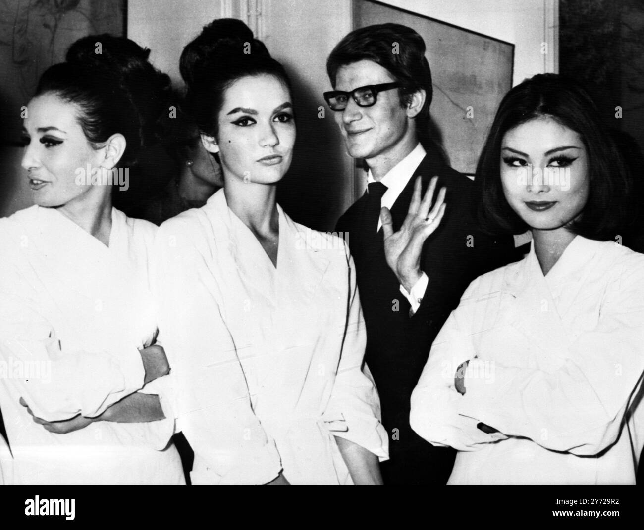 Designer Yves St Laurent waves from behind three of his favourite ...
