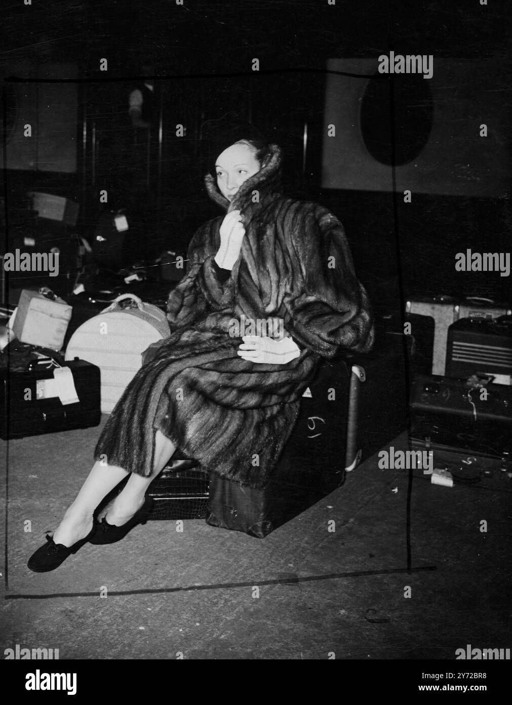 Famous film star Marlene Dietrich sits on her luggage on arrival by the ...