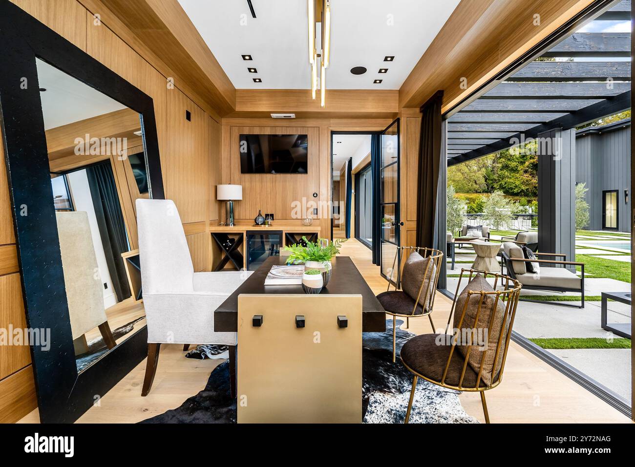 Modern home office with wooden walls, large mirror, and glass doors ...