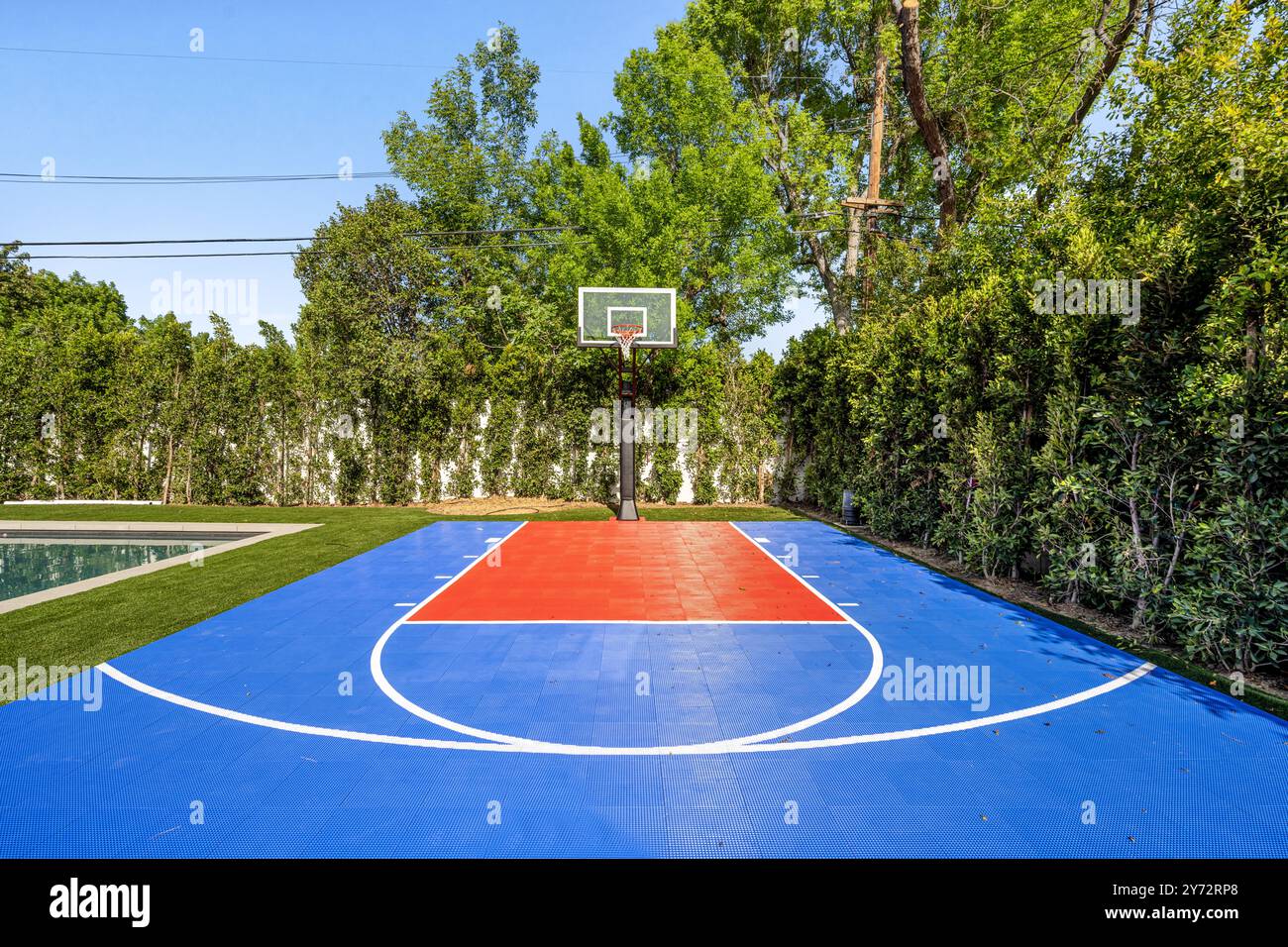 Outdoor basketball court with blue and red flooring, surrounded by ...