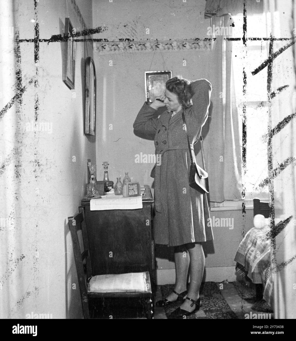 Woman brushing hair in front of the mirror in her bedroom. [no caption ...