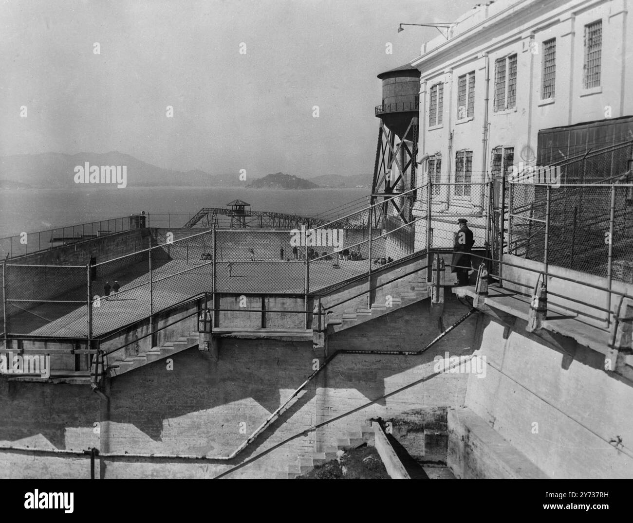 A guard (right) watches as imates (far background) on Alcatraz play ...