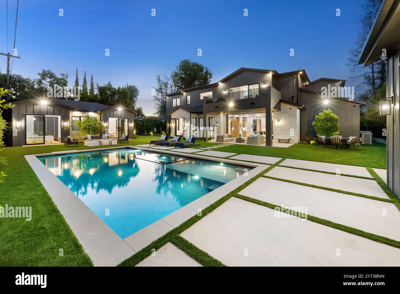 A modern luxury house with a swimming pool, outdoor seating, and well ...