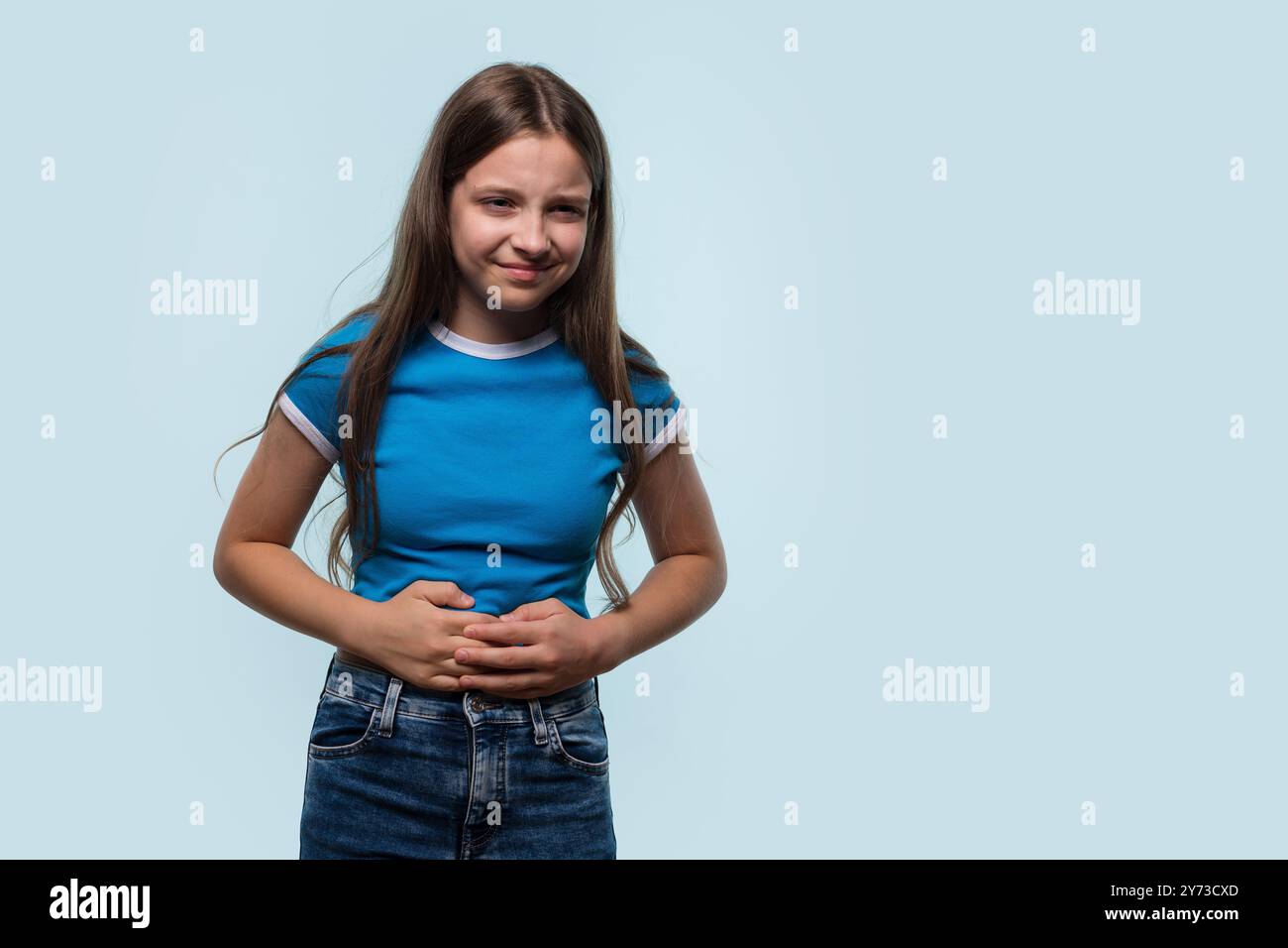 A young girl holding her stomach, showing signs of abdominal discomfort ...