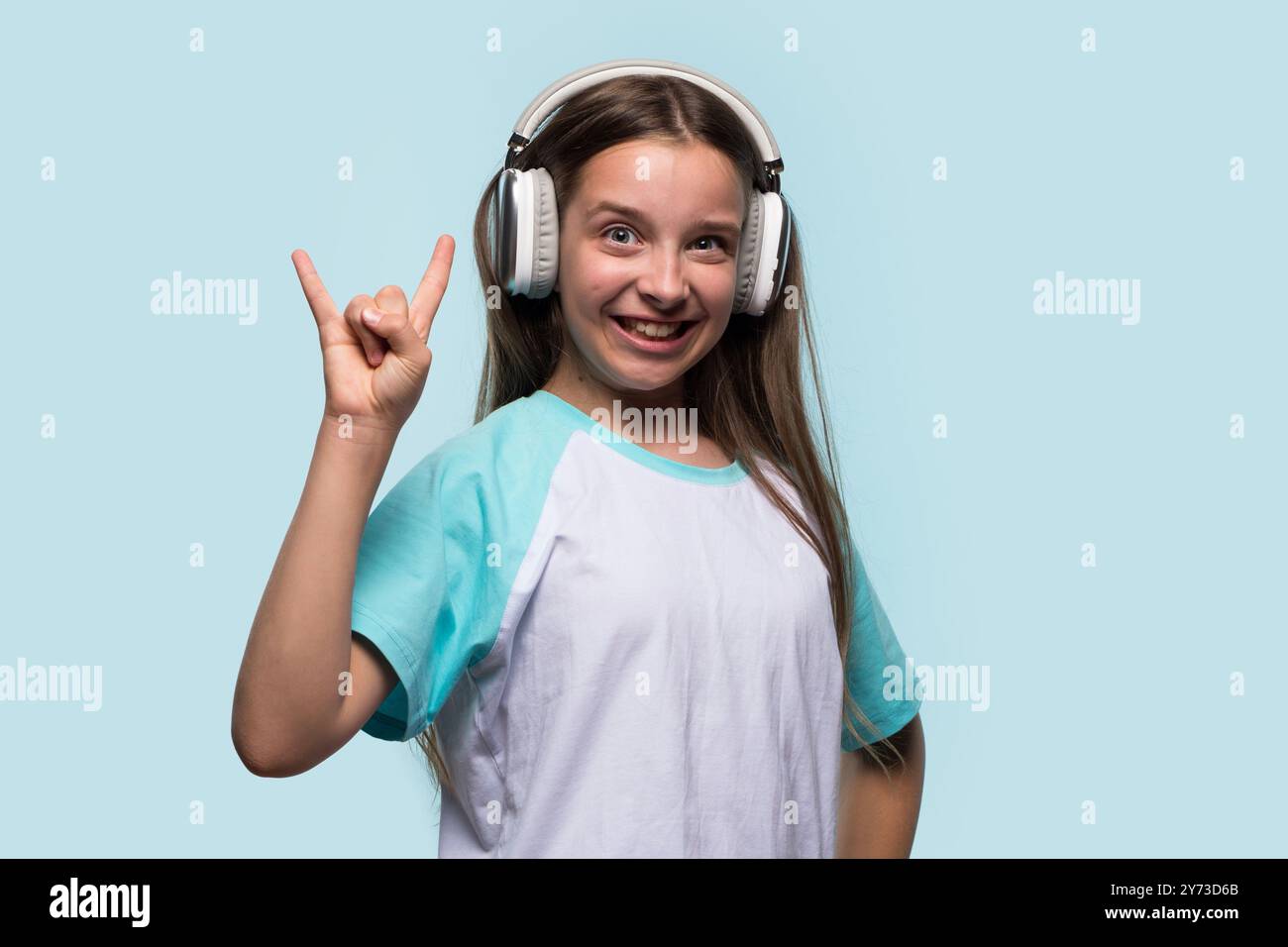 Excited girl making a rock hand gesture while wearing headphones ...
