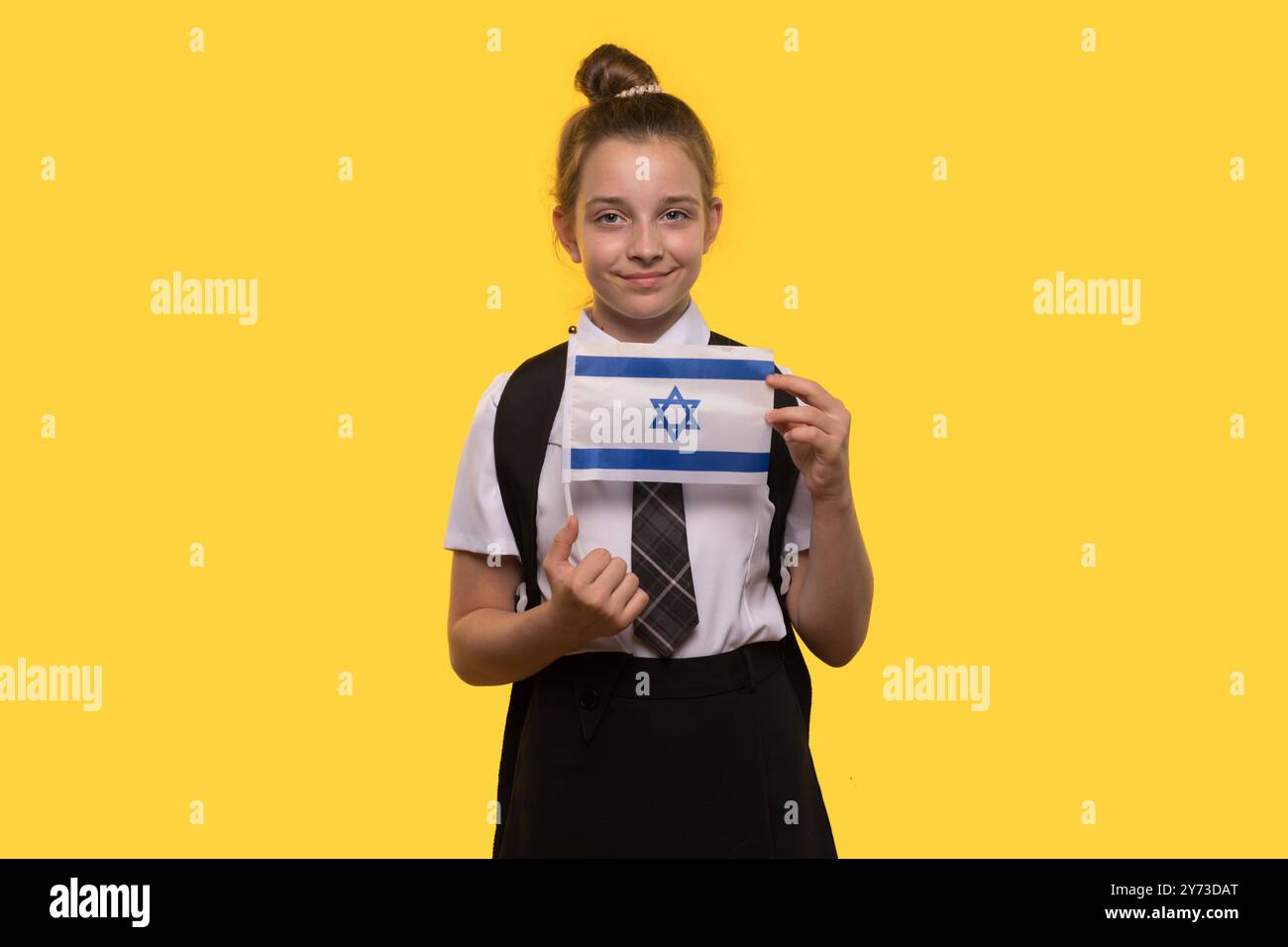 A smiling schoolgirl proudly holds the Israeli flag while posing Stock ...