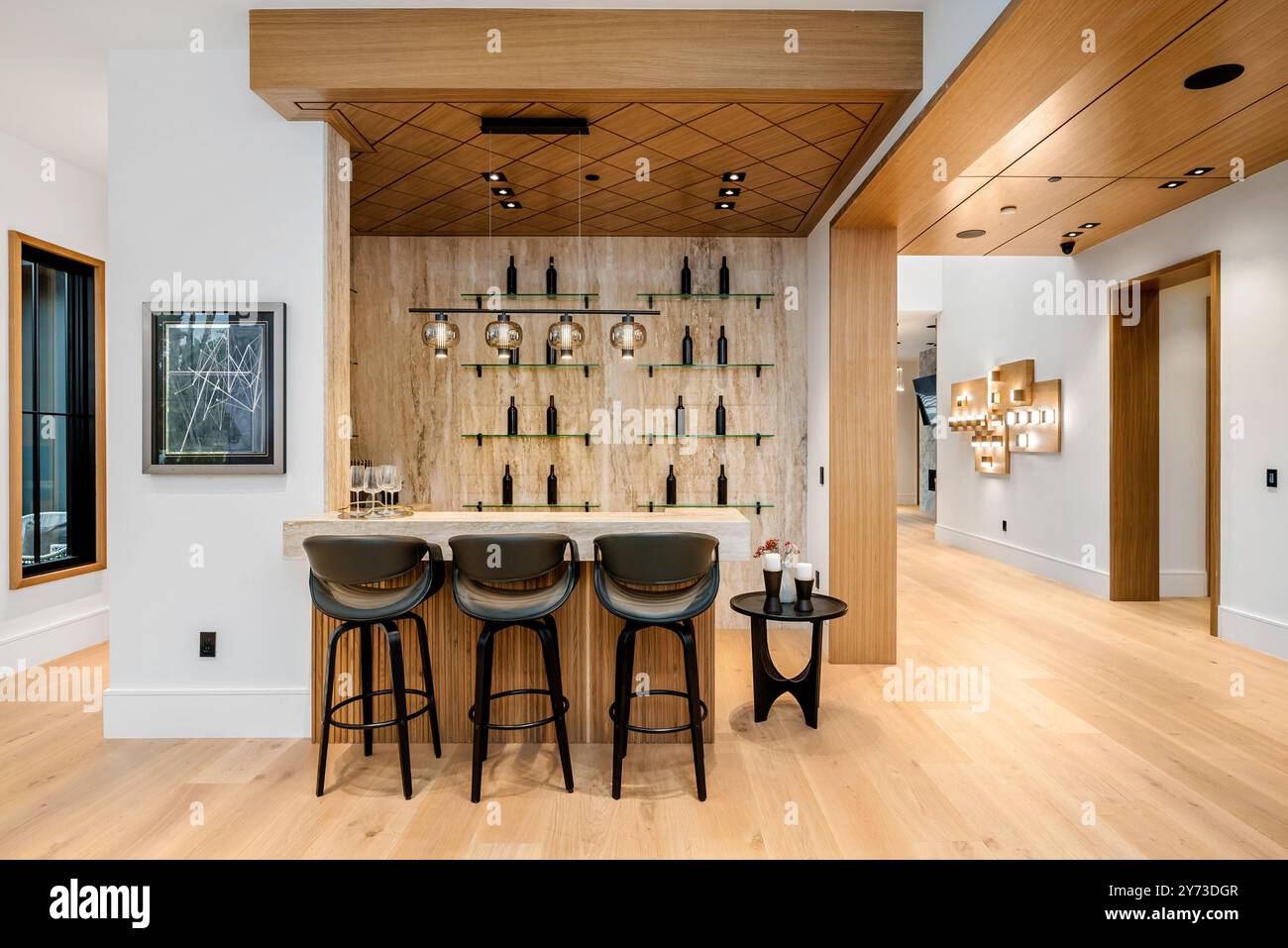 Modern home bar with wooden accents, bar stools, and glass shelves ...