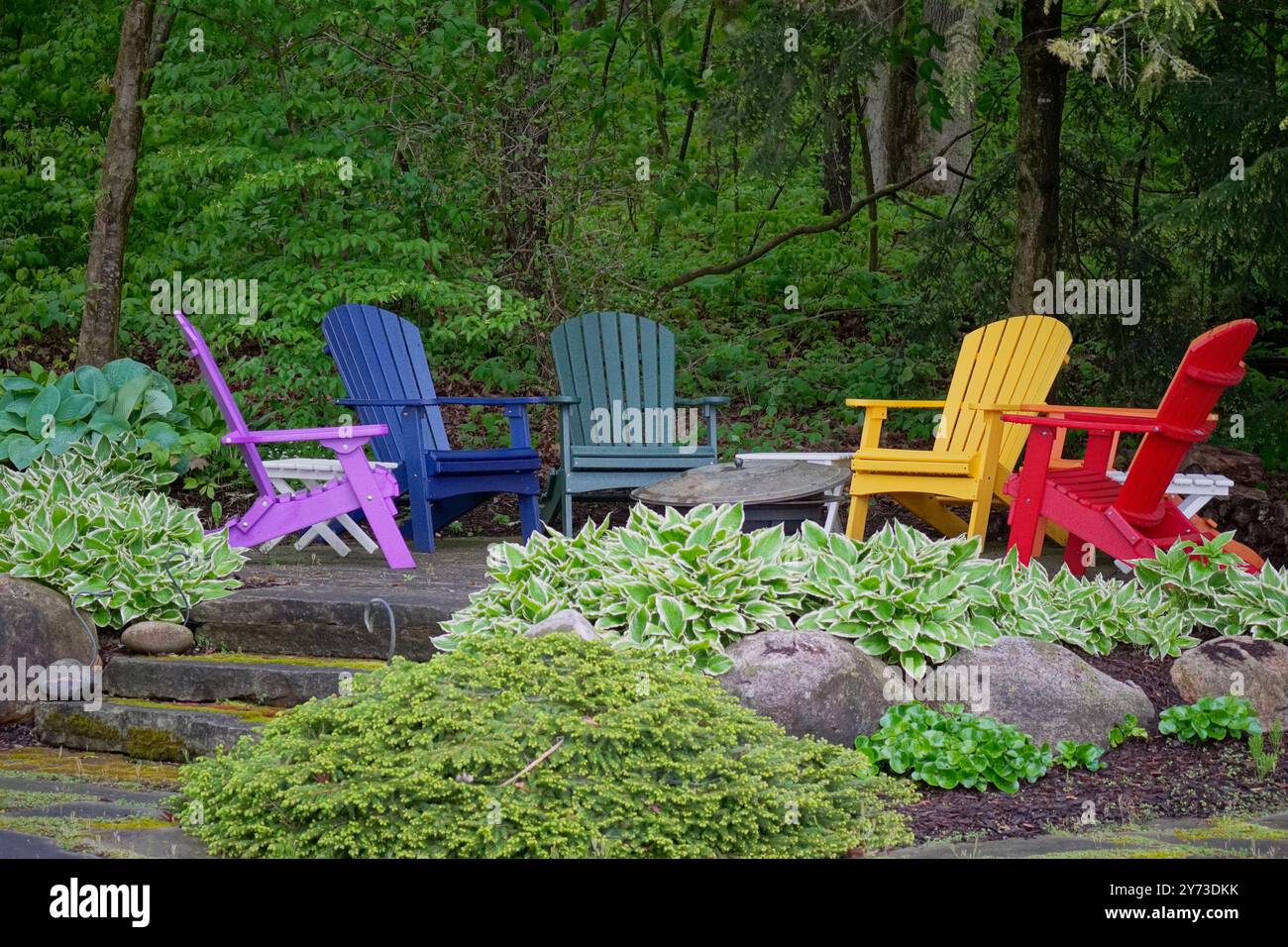 Group of colorful chairs in a flower garden Stock Photo - Alamy