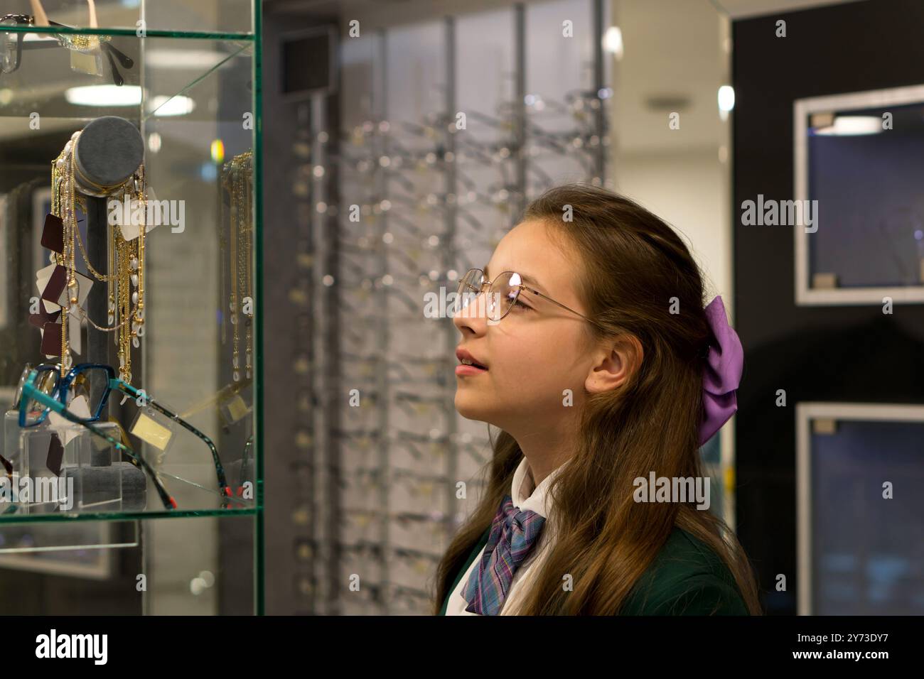 Girl in a school uniform examining glasses and accessories in an ...