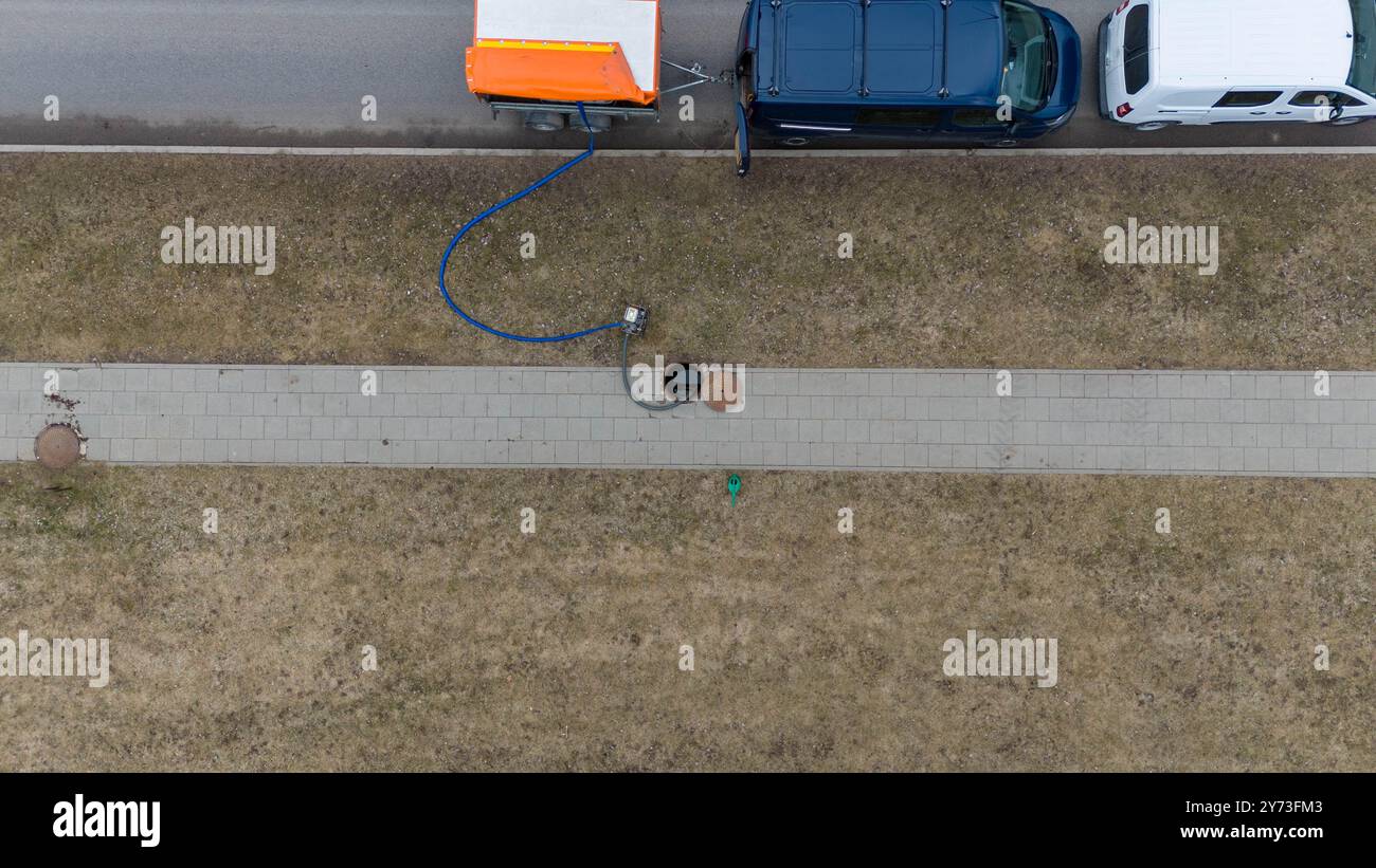 An aerial view of a two vehicles parked along a road. A group of people ...
