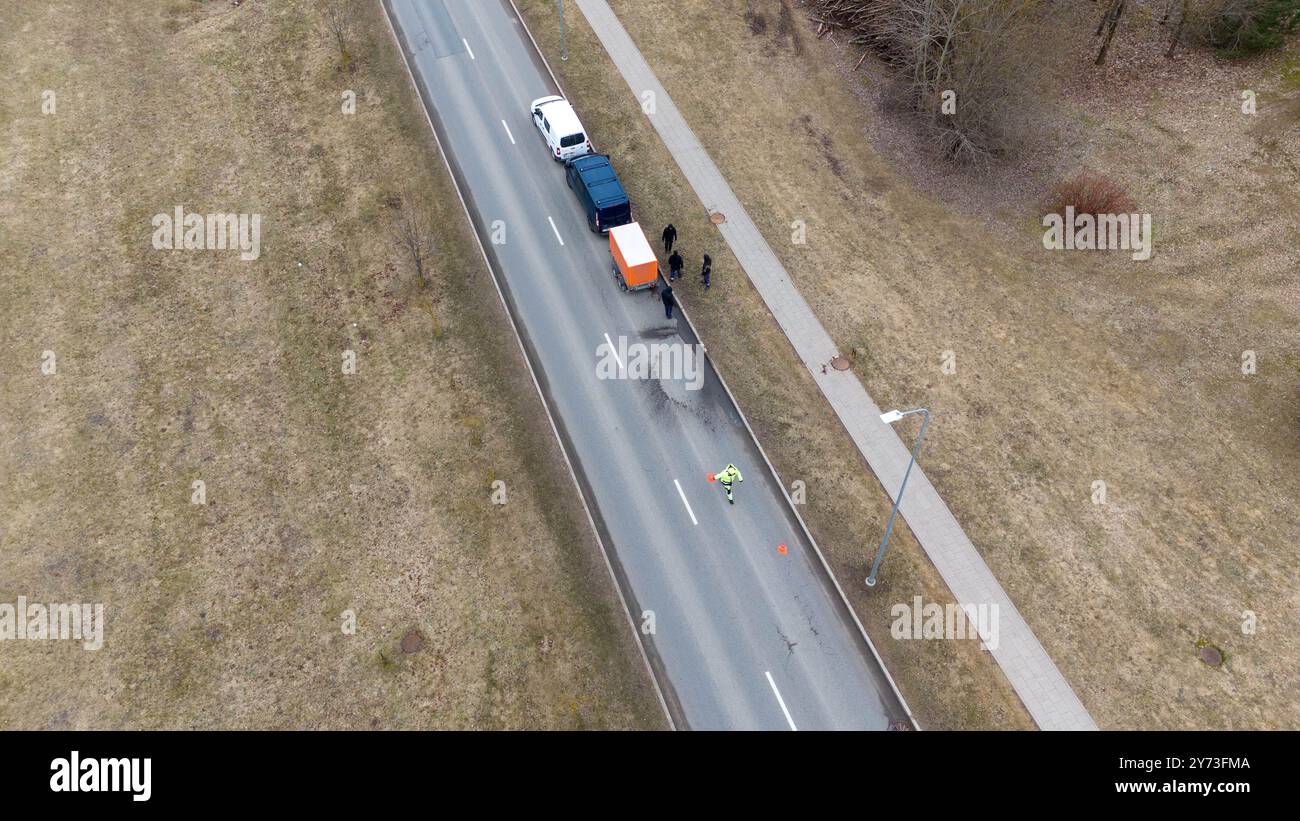 An aerial view of a two vehicles parked along a road. A group of people ...