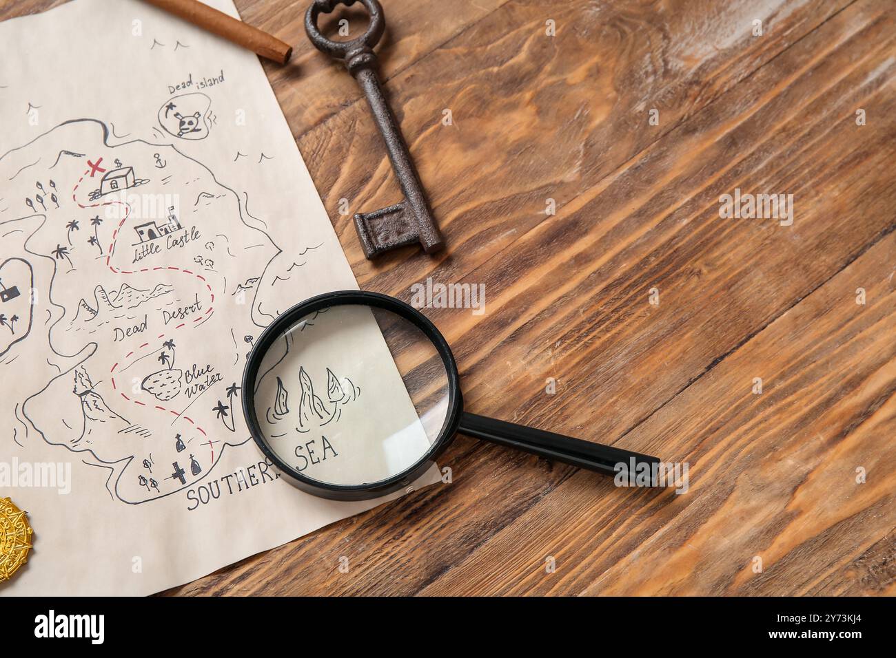 Treasure map with magnifier, key and pirate amulet on brown wooden ...