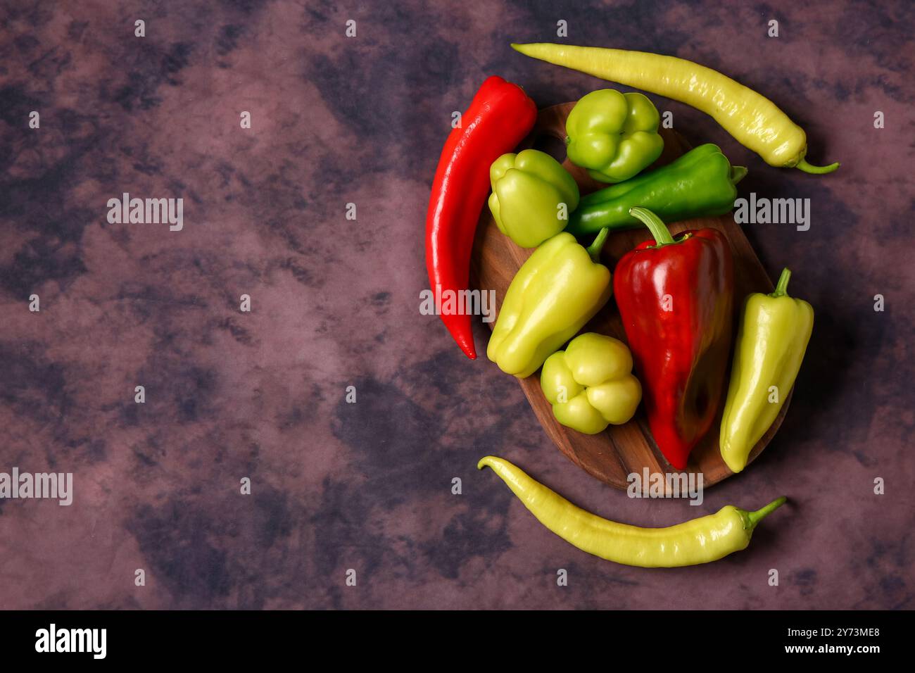 Wooden board with different fresh peppers on purple background Stock ...