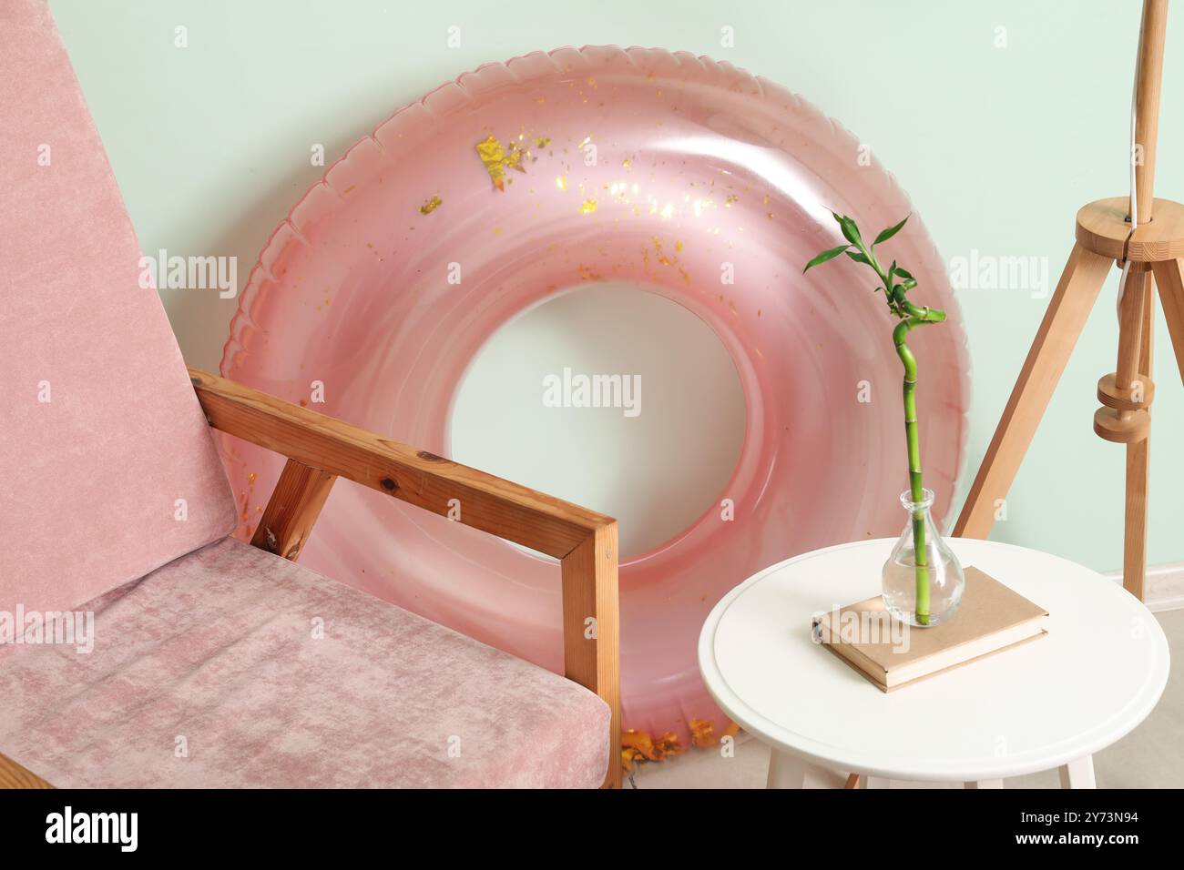 Chair, stool with vase and inflatable ring near pale green wall in room ...