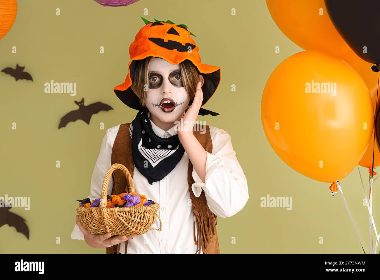 Shocked little boy dressed for Halloween with candies and balloons near ...