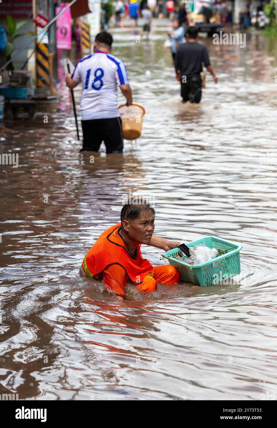 Highway worker clears debris from a drain after flash floods caused by ...