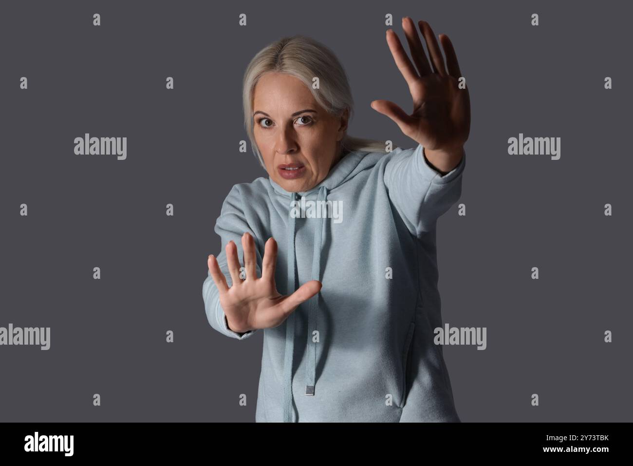 Mature woman having panic attack on grey background Stock Photo - Alamy