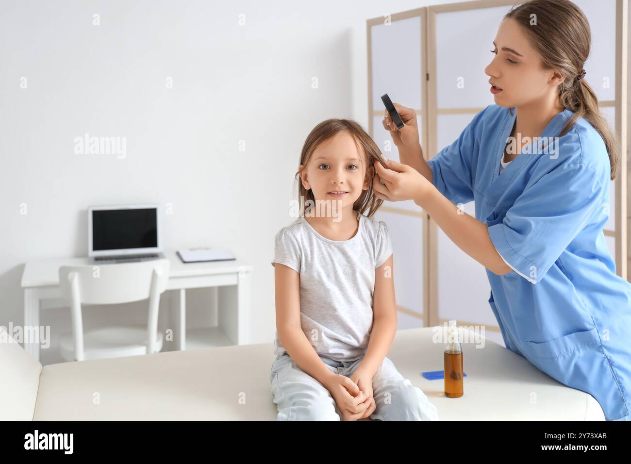 Female doctor with magnifier checking little girl's head for ...