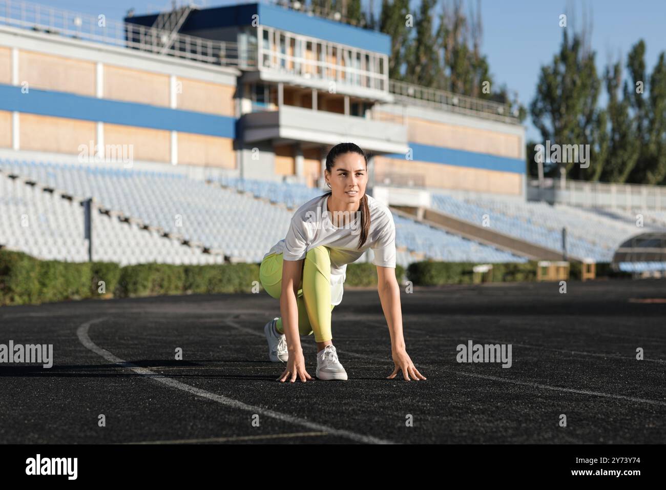 Sporty young woman in crouch start position at stadium Stock Photo - Alamy