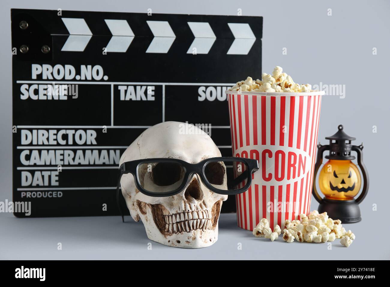 Human skull with 3D glasses, clapperboard, tasty popcorn and lantern ...
