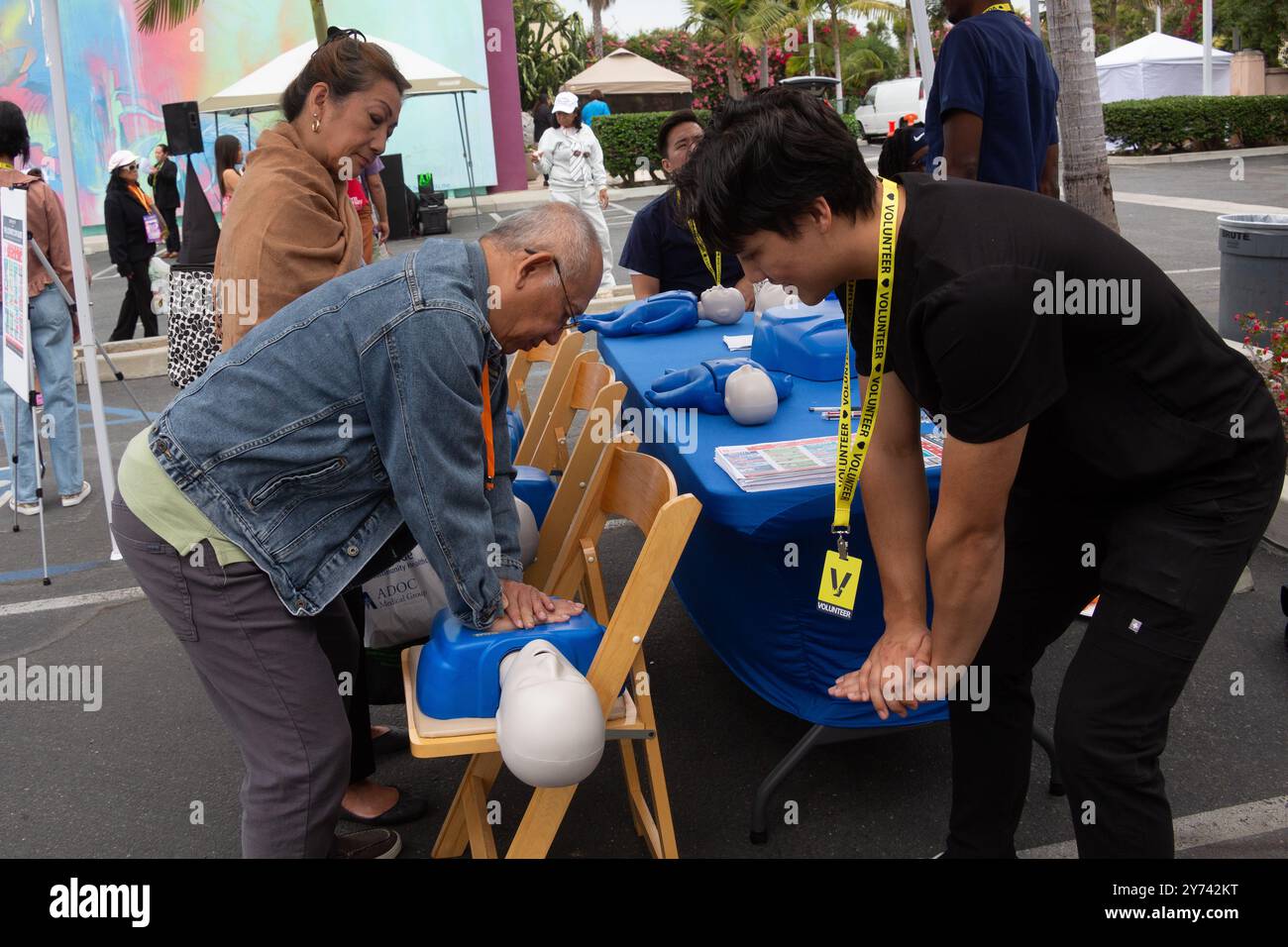 An Asian American male volunteer shows an Asian American man how to do ...