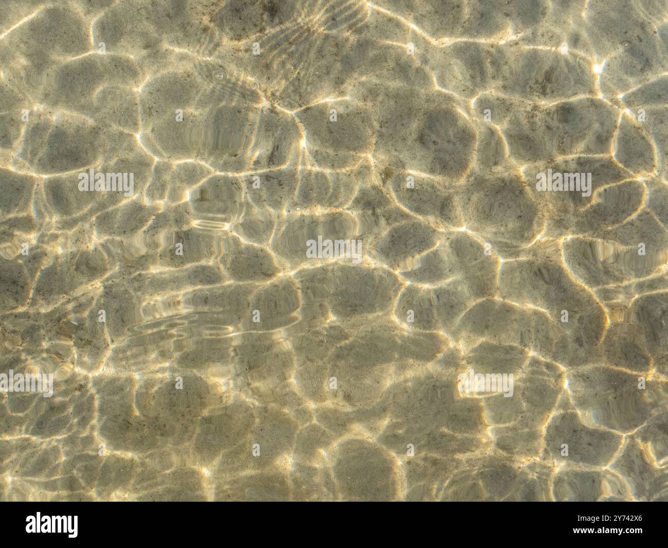 The texture of the sand and the reflections of light on gently rippling ...