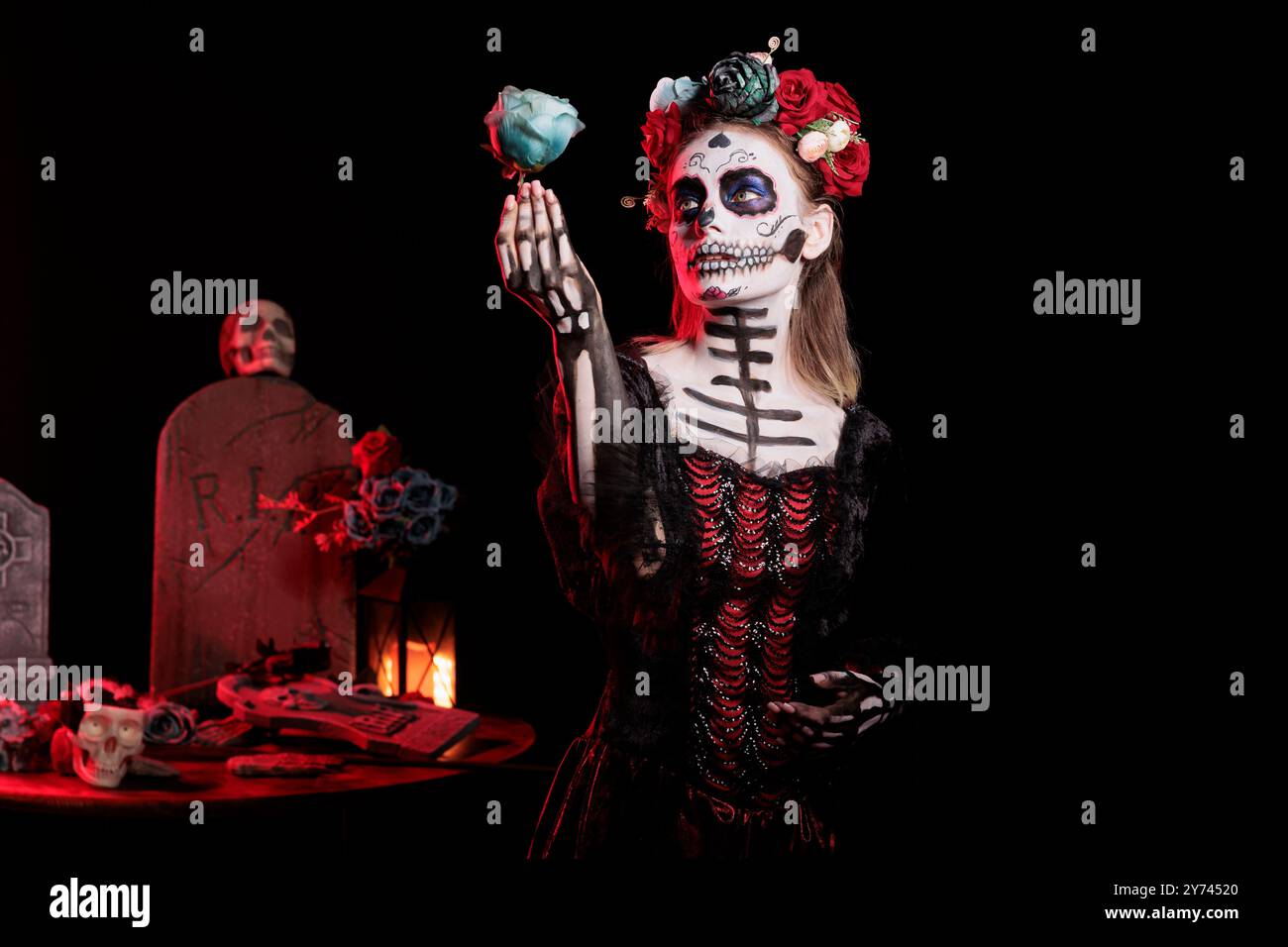 Woman looking at blue rose against dark background grave site ...