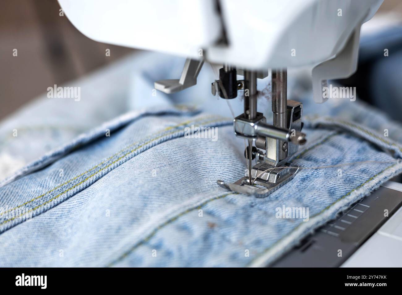 Close-up of a sewing machine foot making a stitch on blue jeans Stock ...