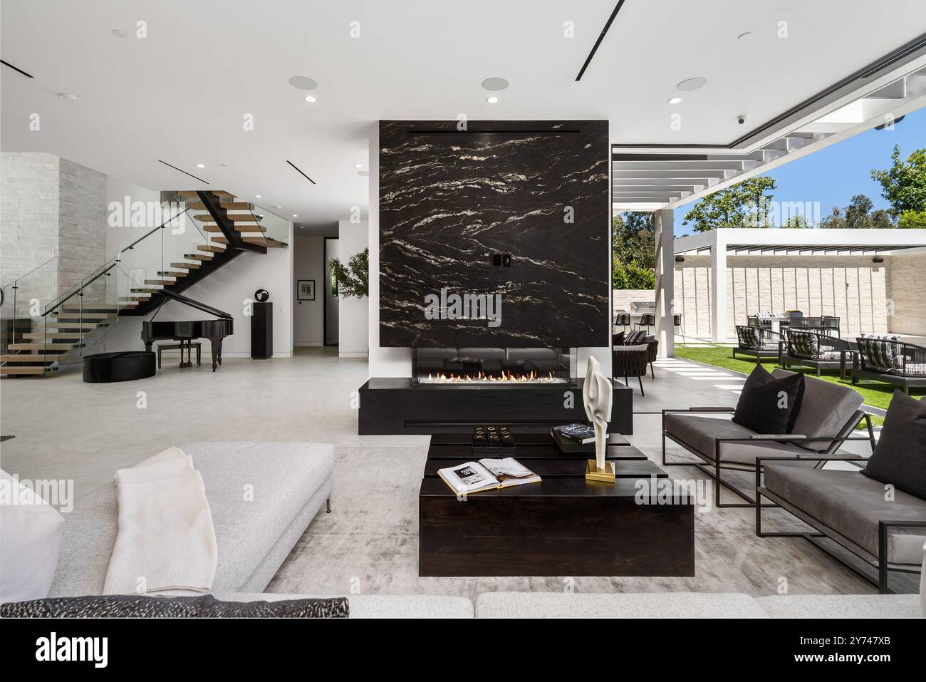 A modern living room interior with a black marble fireplace, open floor ...
