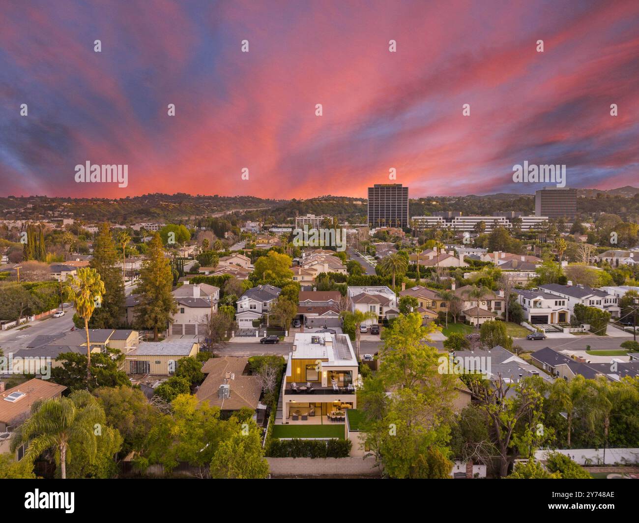 Aerial view of a suburban neighborhood with a vibrant sunset sky ...
