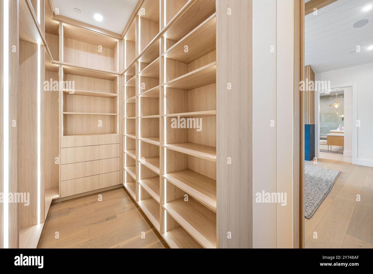 Modern wooden walk-in closet with ample shelving and drawers ...