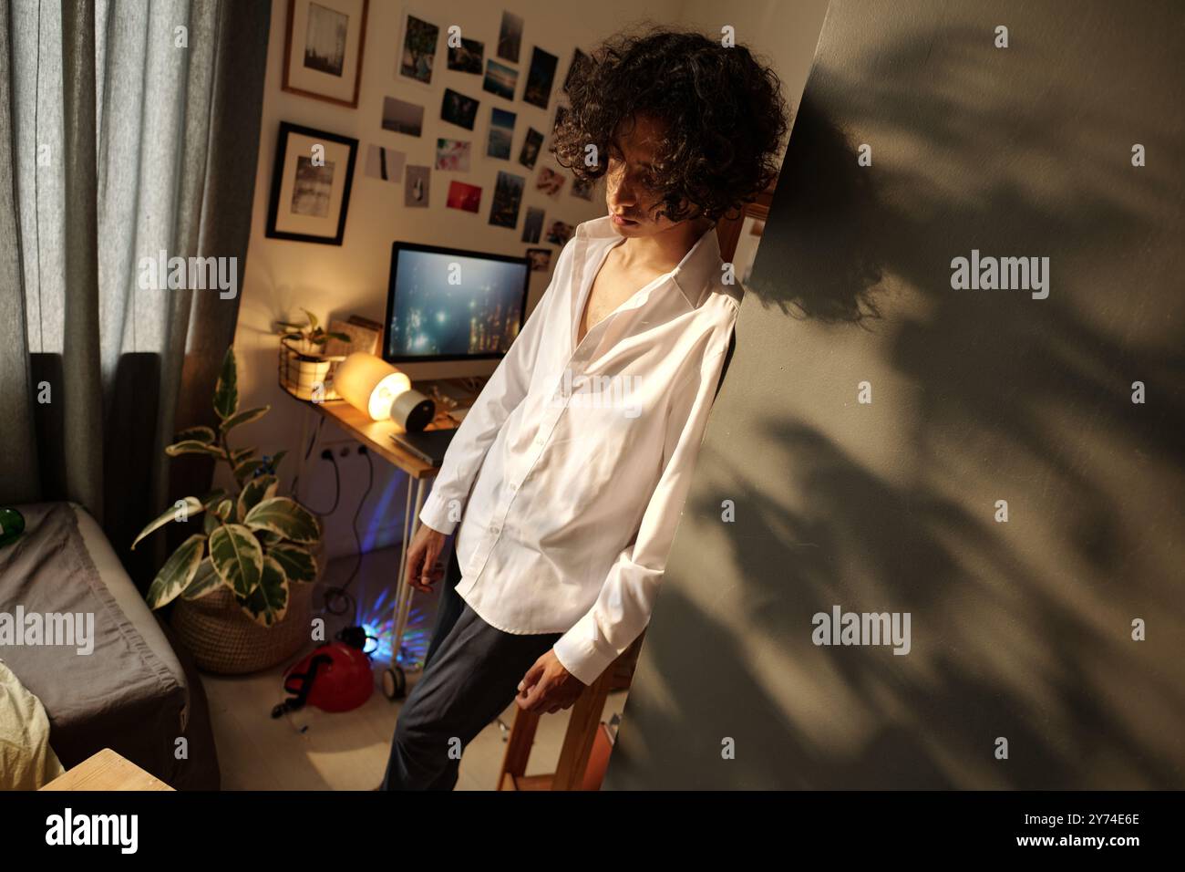 Drunk teenage guy in white shirt standing by corner in home environment ...