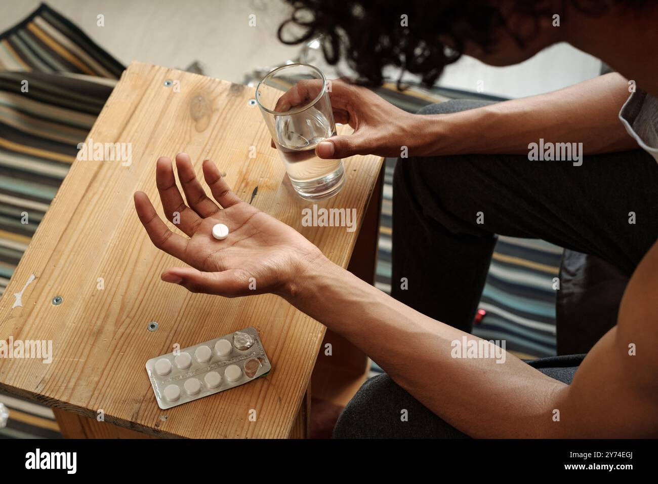 High angle of hands of young drunk man holding pill and glass of water ...