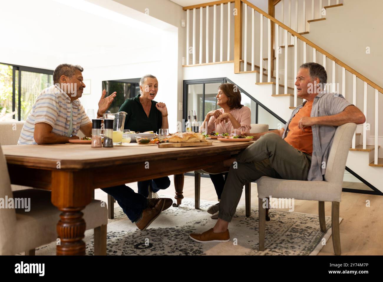 Seniors enjoying meal and conversation around dining table in modern ...